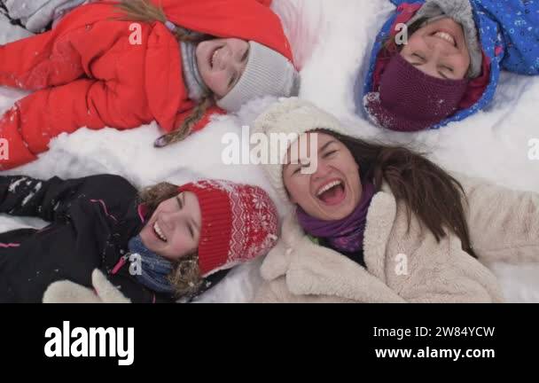 Two women and two teenage girls lie in the snow, and someone is pouring ...