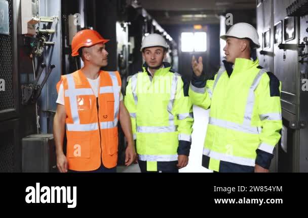 Engineers in uniform and helmets do pre-commissioning works inspecting ...