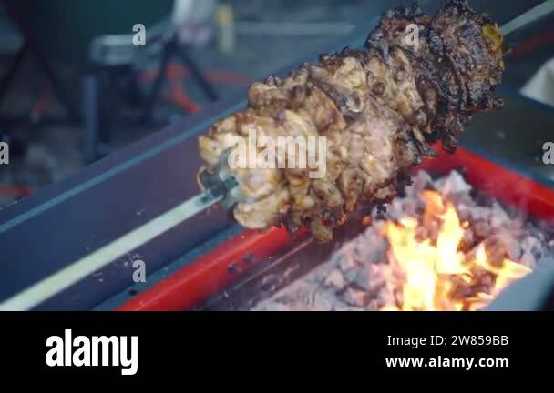 Top view shot of rotating bbq skewer with fat pork meat dropping oil ...