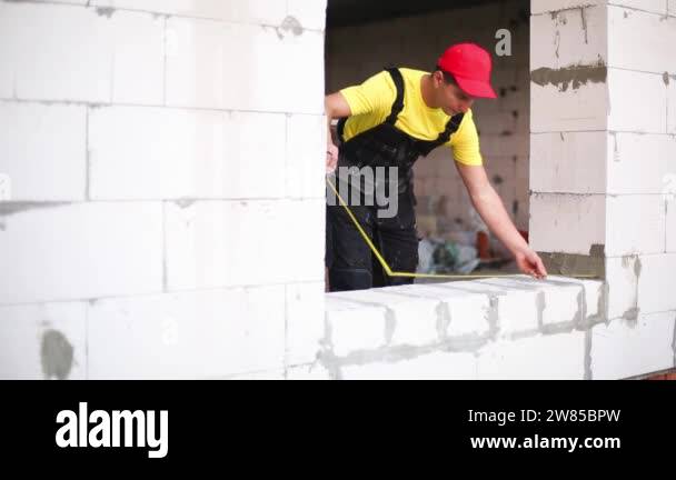 Construction worker at construction site measures the length of window ...