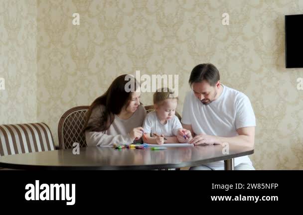 Family education. A little girl, with her parents, draws with colored ...