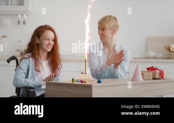 Family birthday party. Little girl with disability looking at cake with ...