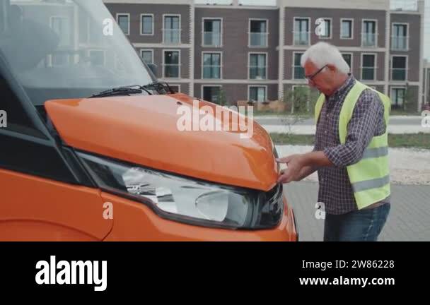 Medium handheld shot of senior bus driver in acid green vest opening ...