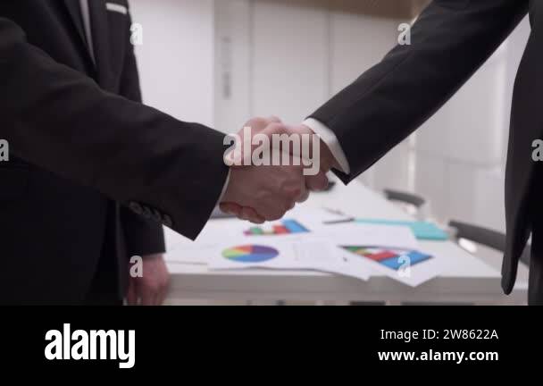 Close-up handshake of two Caucasian businessmen in office indoors ...