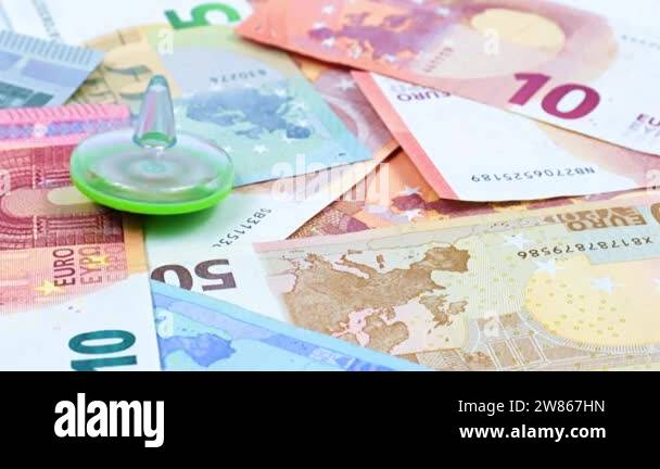 a plastic spinner whirligig rotates on a pile of euro banknotes as a ...