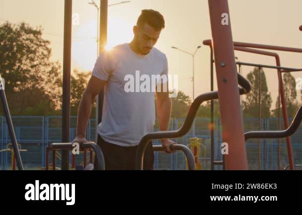 Strong Arab man performs push-ups on bars develops biceps and trapezius ...