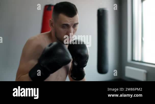 Kickboxer in boxing gloves does shadow boxing and trains at boxing club ...