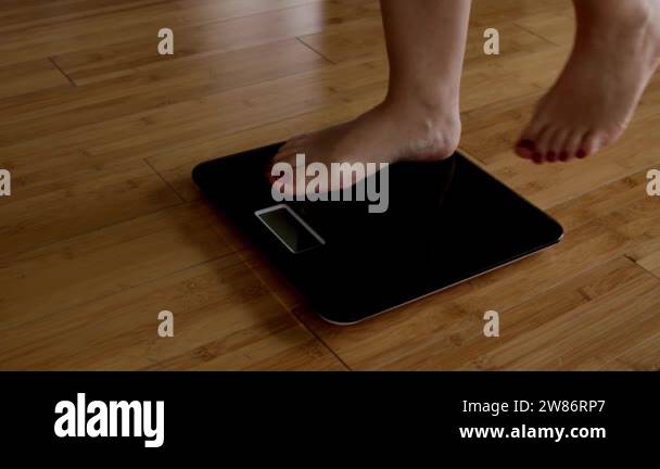 Woman is measuring her weight on the scales.Girls feet step on the ...