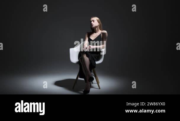 Beautiful fashion model sitting on chair with legs crossed Stock Video ...