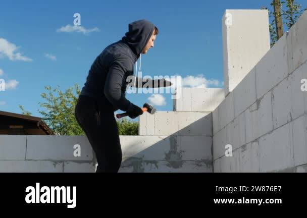 Man at the construction site. A man builds a house with his own hands ...