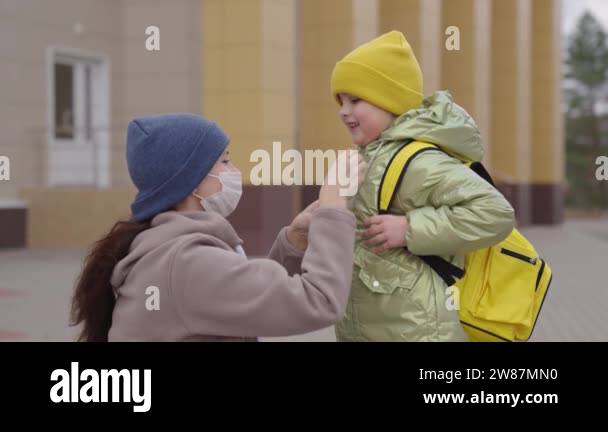 mother wears child with backpack with medical mask schoolyard, mother ...