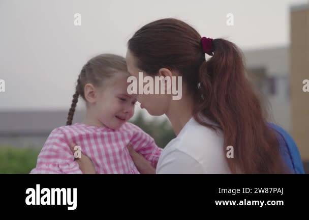 mother calms and hugs little girl, upset kid sheds tears from his eyes ...