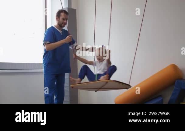 Child girl with physiotherapist swinging on swing during sensory ...