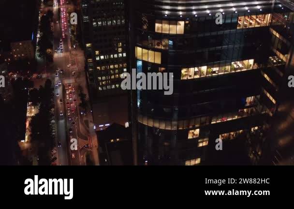 Modern high rise office building with glossy facade reflecting lights ...