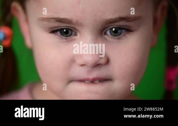 Little girl blinking eyes, slow motion of a child, portrait on a green ...