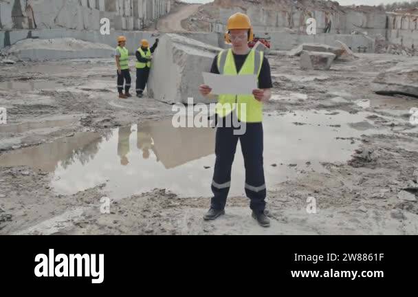 Slowmo tracking of male supervisor in hard hat, safety goggles and ...