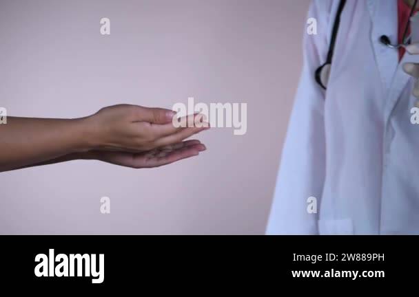 A senior doctor in a white uniform sanitizing her patient's hands in ...