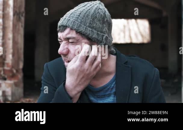 a hungry homeless unshaven man without teeth on the street in a torn ...