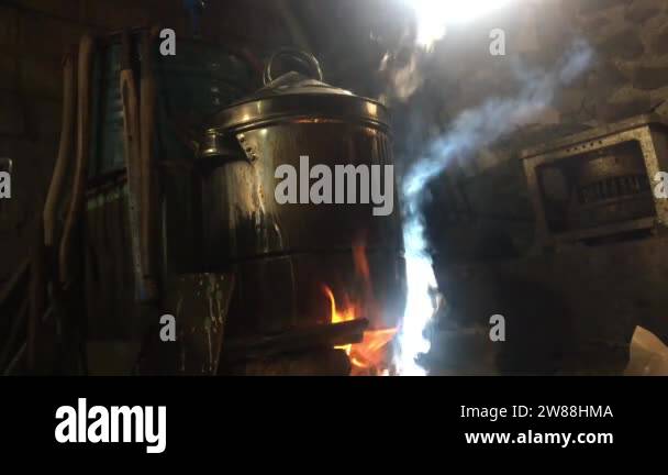 Cook with boiler in traditional stove or kitchen with wood fire and ...