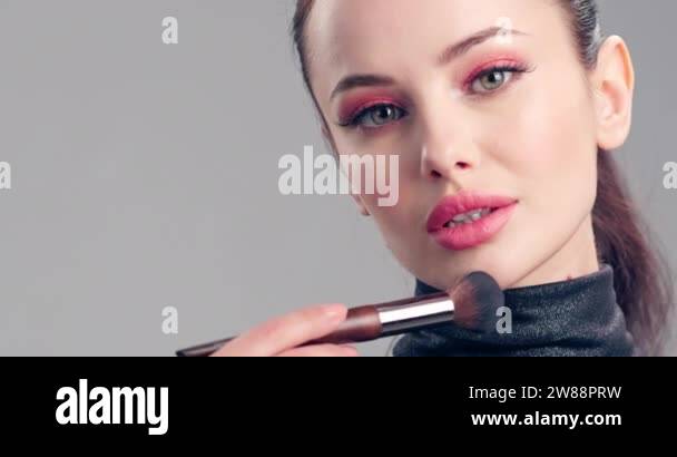 Woman makes makeup. Young woman makes blush on the face using makeup ...