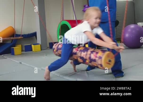 Child girl with physiotherapist swinging on swing during sensory ...