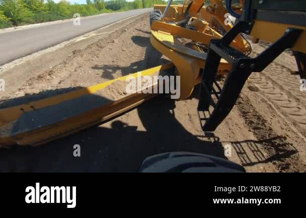 Grader levels ground for construction of new road or highway, blade ...