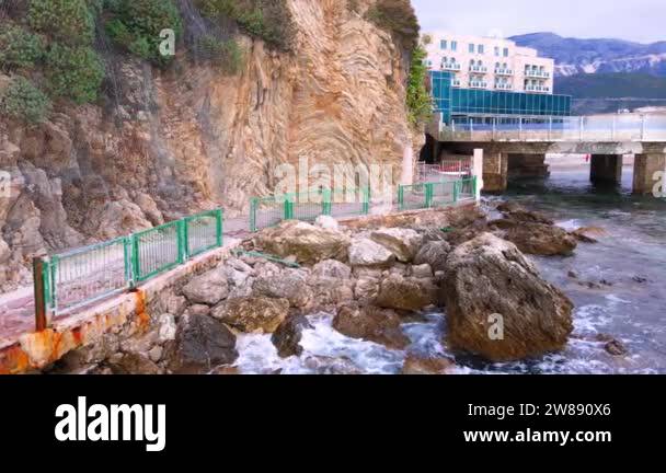 Path to embankment along sea coastline at the foot of cliff, iron fence ...