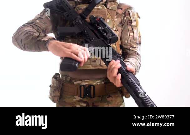 Man in combat camouflage and body armor attaches an ammunition magazine ...