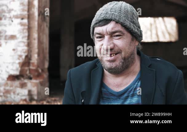 a hungry homeless unshaven man on the street in a torn suit a beggar ...