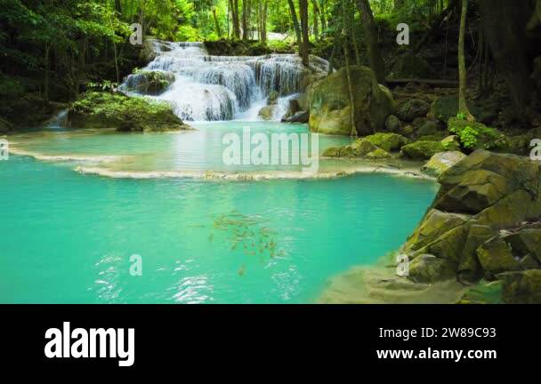 Waterfalls and fish swim in the emerald blue water in Erawan National ...