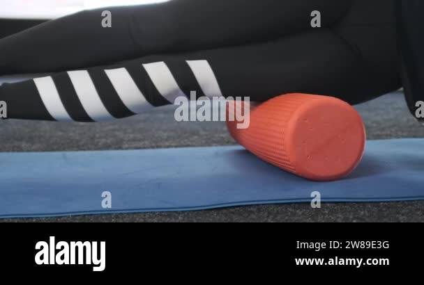 Woman kneads muscles of thighs with myofascial roll. Working out deep ...