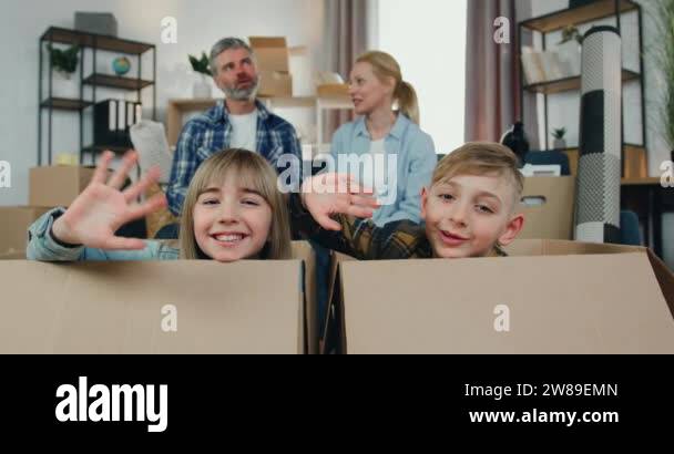 Lovely satisfied cheerful boy and girl sitting in carton boxes and ...