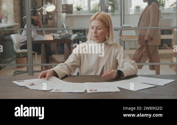 Portrait shot of middle-aged female HR manager with blond hair sitting ...