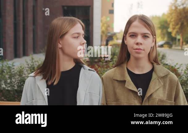Handheld tracking portrait shot of young identical twin sisters sitting ...