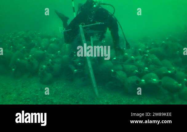 Underwater archeology: a diver takes a sample of bottom sediments near ...
