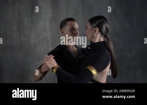 The young dance ballroom couple in gold dress dancing in sensual pose on studio background ...
