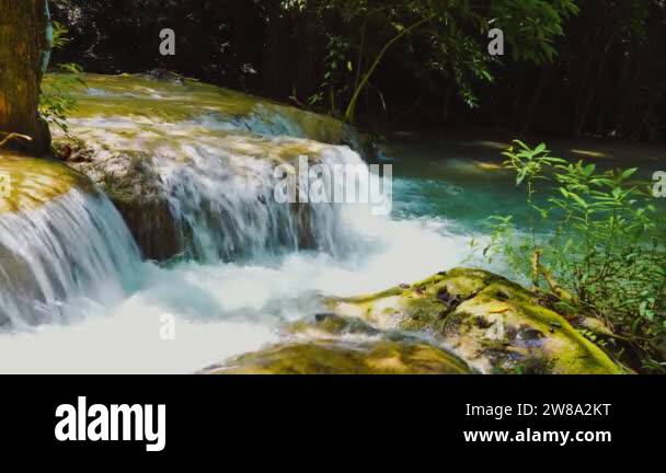 Waterfalls and fish swim in the emerald blue water in Erawan National ...