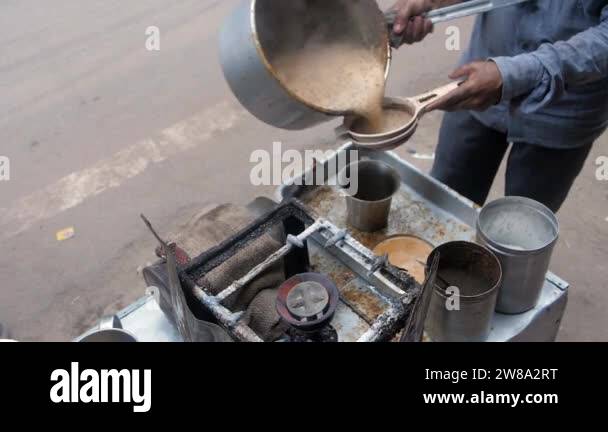 A local tea seller at a small shop serving freshly made tea in a big ...