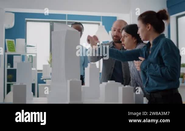 Team Of Architects Analyzing Building Model To Plan Construction Layout And Blueprints Stock