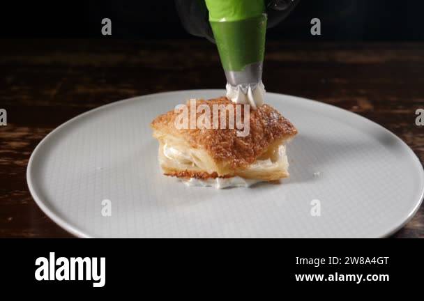 Chef cooking and serving dessert. Pouring whipped cream on cake. Sweet ...