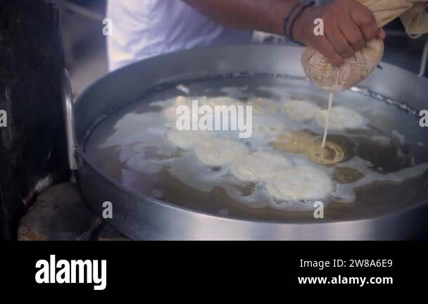 A man making hot Jalebis in a roadside shop - Indian sweets. An old ...