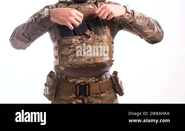 Man in combat camouflage and body armor inserts rifle magazines into ...