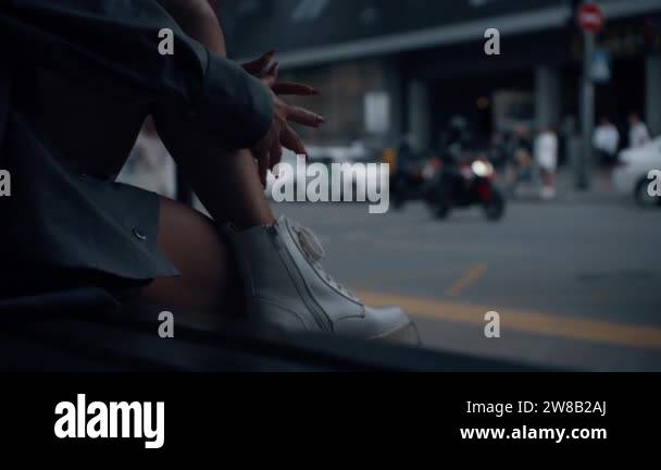 Woman legs sitting city background on bus stop near crowded street ...