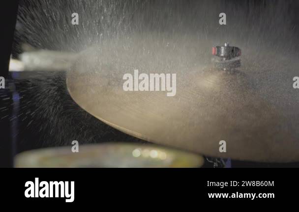 The drummer hits the wet drum cymbal with his drumstick and the water ...