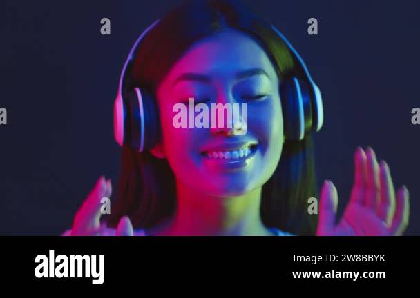 Modern music. Young asian lady wearing wireless headset enjoying ...