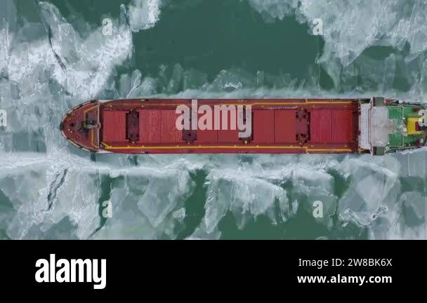Aerial above epic huge steel icebreaker breaks ice by bow of ship and ...