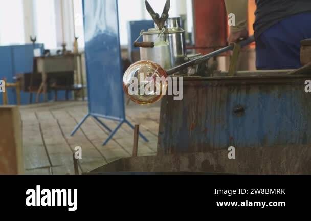 Employee turns hot glass ball workpiece over cooling basin Stock Video ...