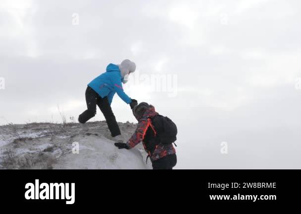 Tourist climbers man and woman stretch out their hands to each other, help climb to top of hill ...