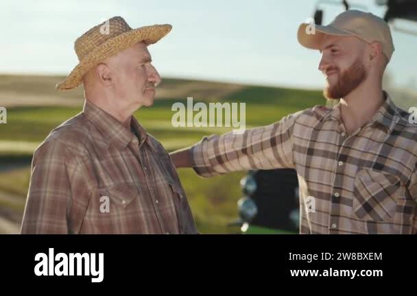 Two farmers are hugging and looking at the camera. They are smiling ...