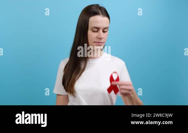 Concept World AIDS and hiv day. Young brunette woman holds red ribbon ...